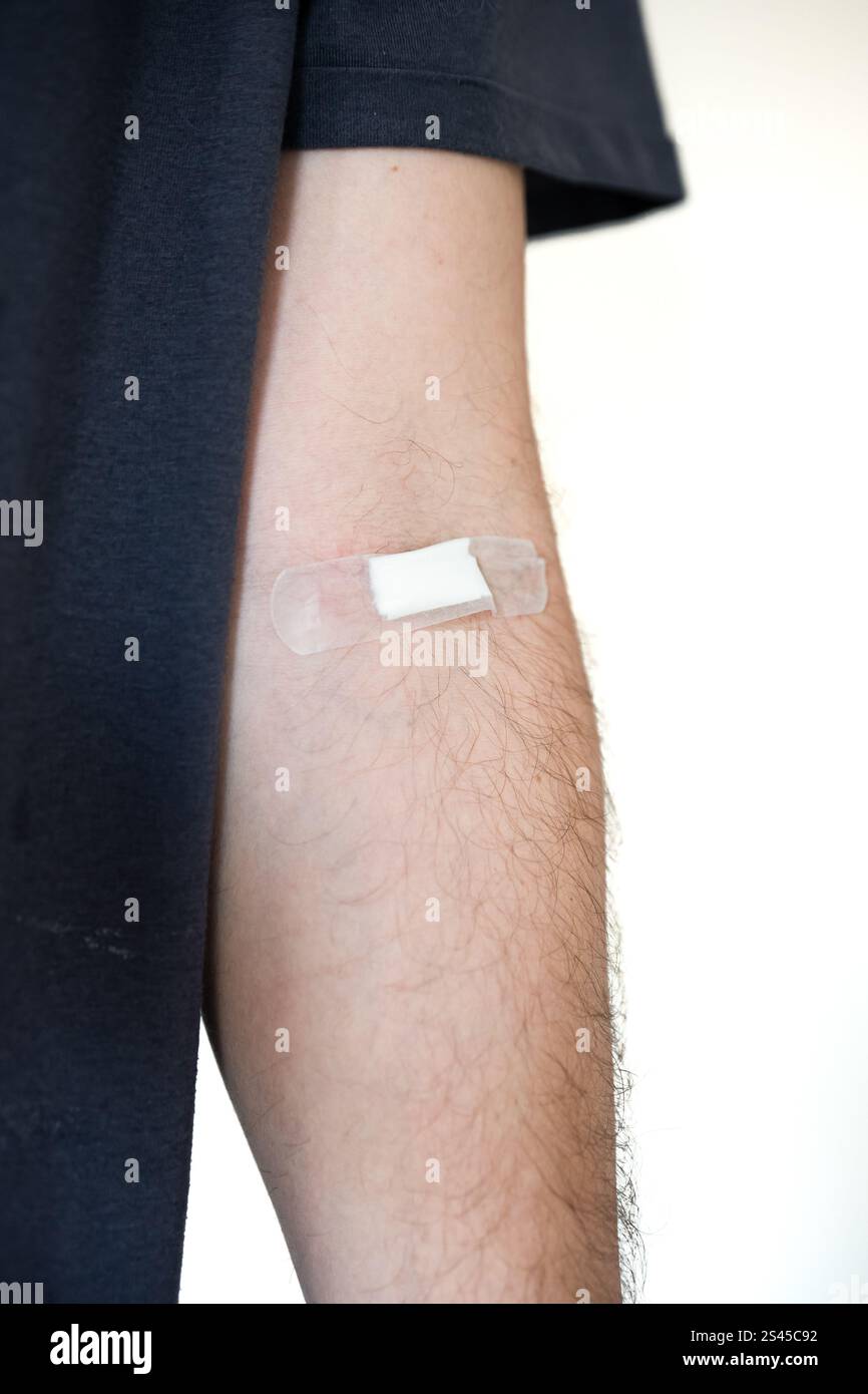 Small plaster and patch on an unrecognizable man's arm after blood test ...