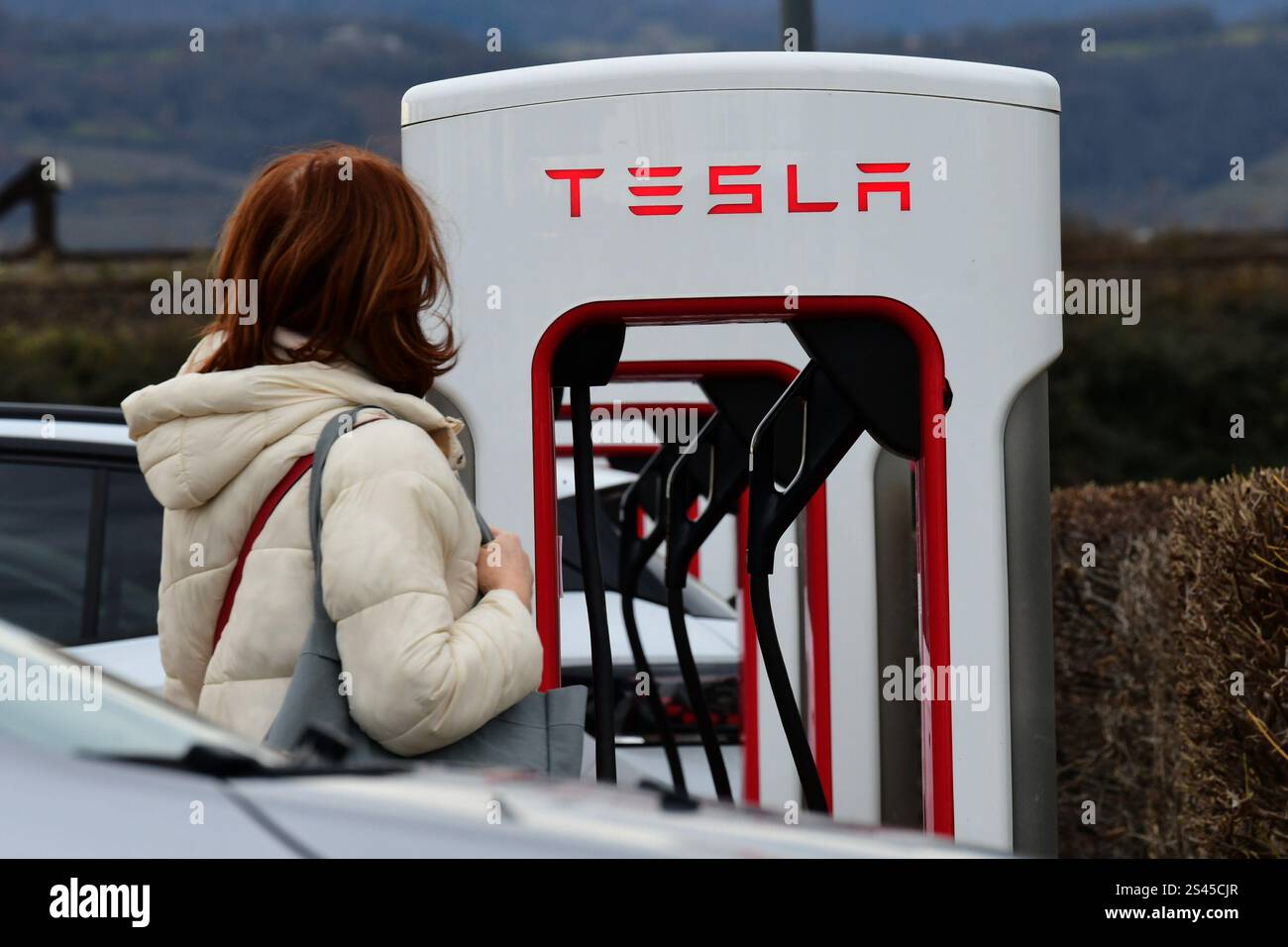 A woman seen at a Tesla electric car charging station Stock Photo - Alamy