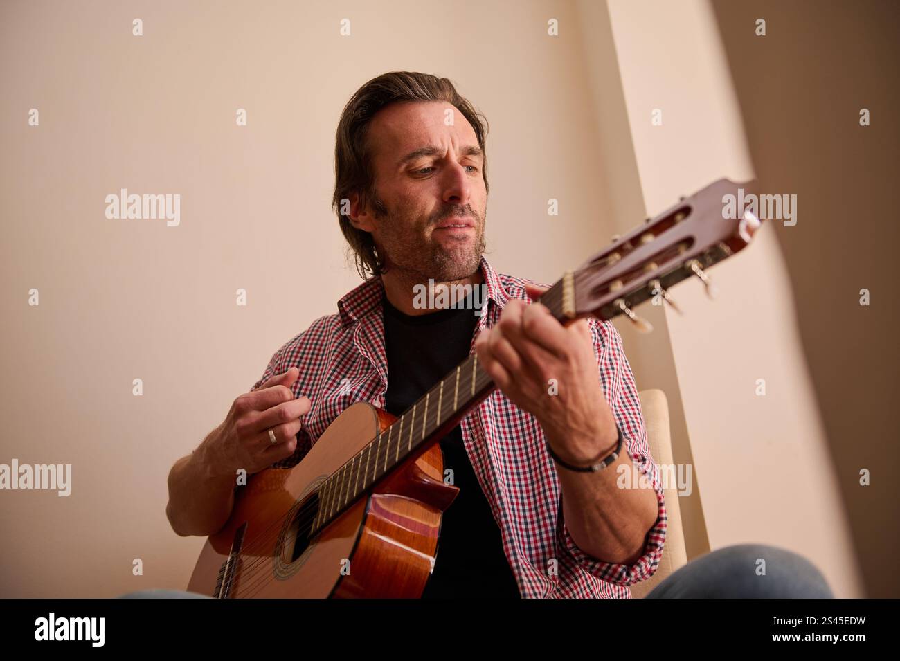 Person strumming a classical guitar indoors, enjoying music and leisure ...