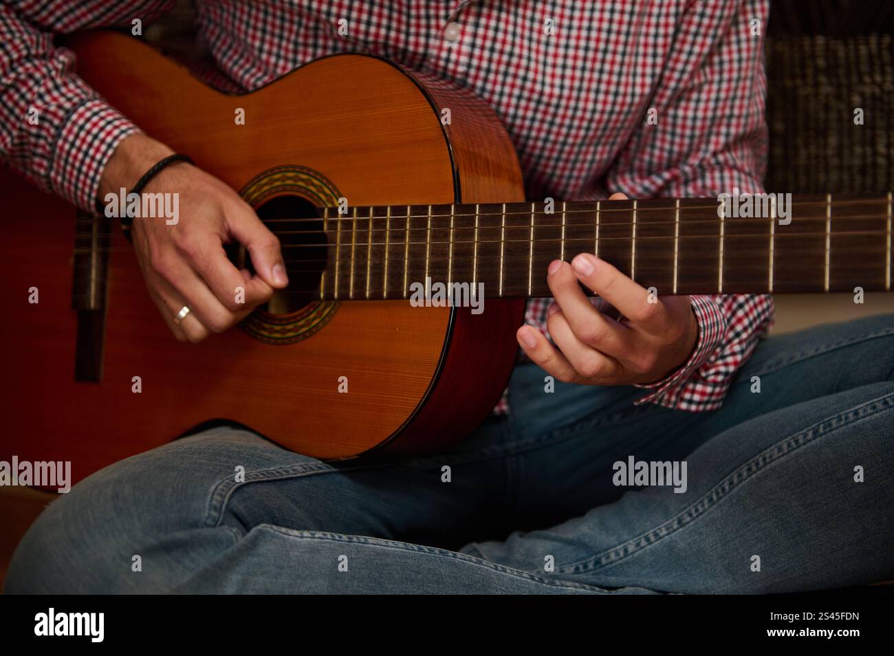 A detailed perspective of hands strumming and fingering an acoustic ...