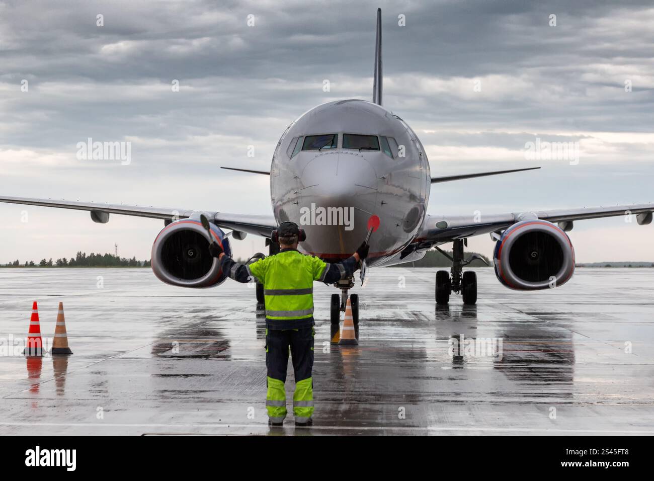 Aircraft marshalling at the aiport in rainy weather. Passenger airplane ...