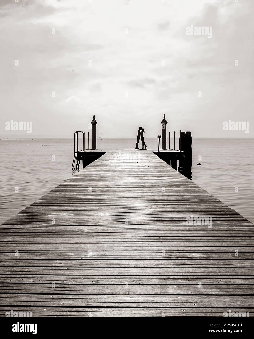 Silhouette of a romantic couple embracing on a wooden pier in ...