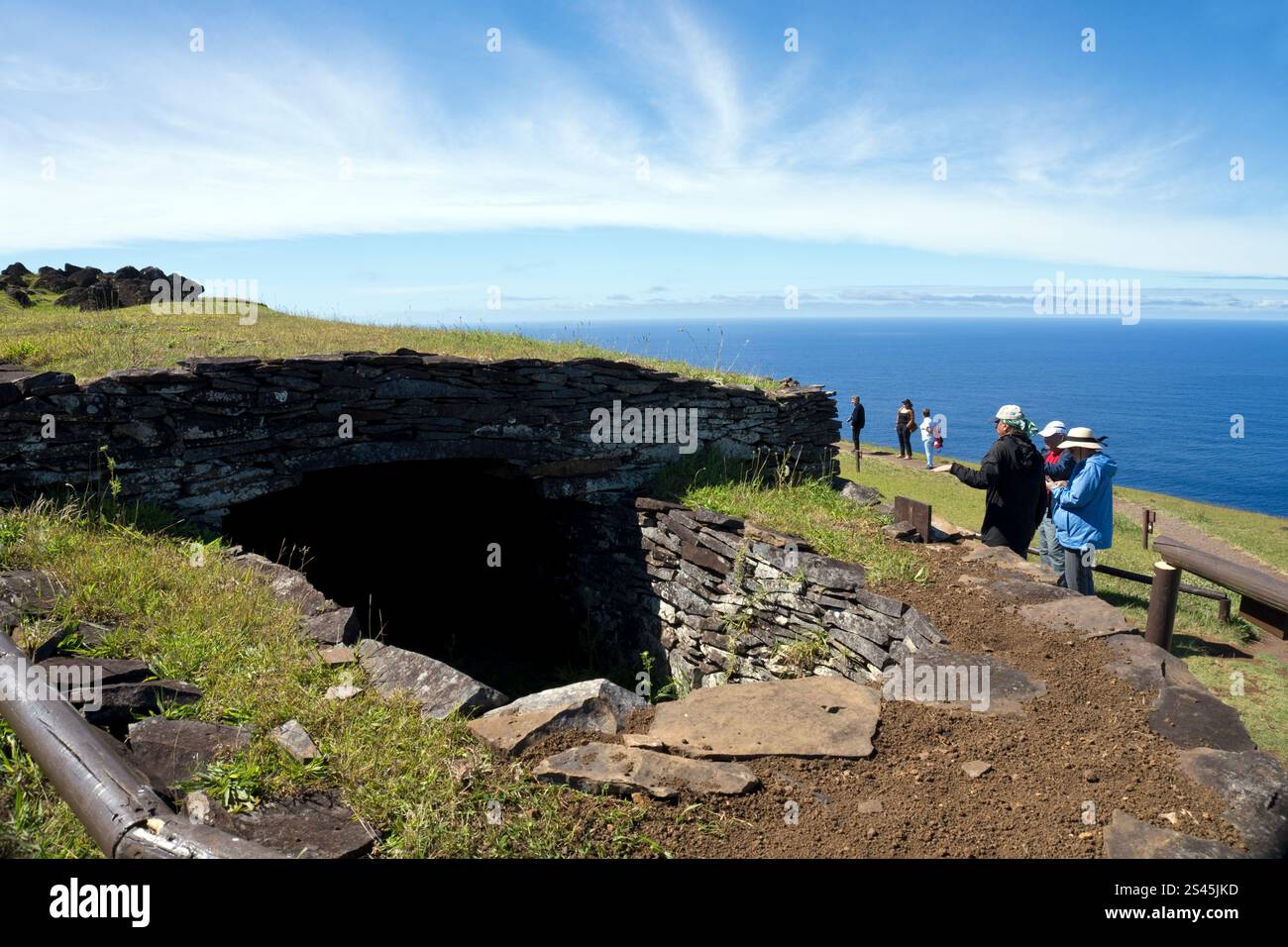 A tour guide explains an open building (for viewing inside) at Orongo ...