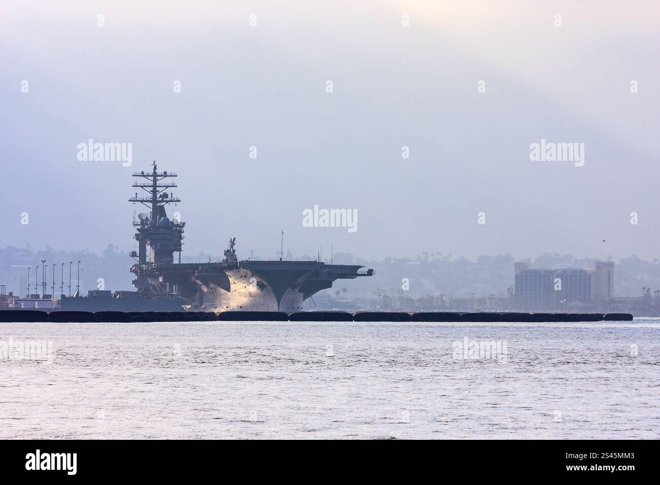 A large Navy ship is sailing in the ocean. The sky is cloudy and the ...