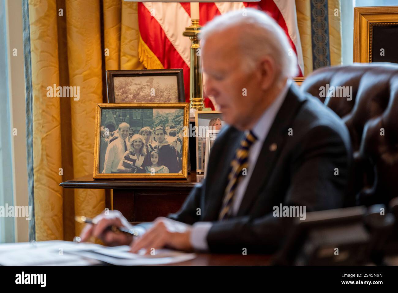 Family photographs sit on a desk behind President Joe Biden, during a ...