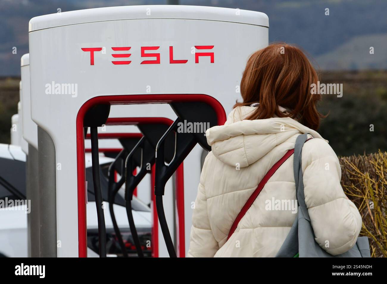 A woman seen at a Tesla electric car charging station. (Photo by Romain ...