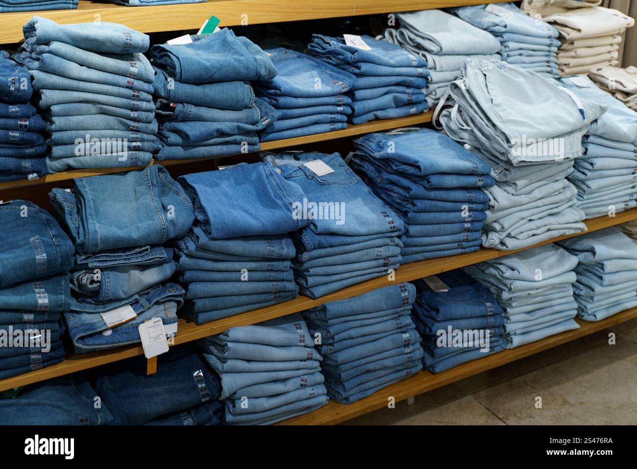 Rows of neatly folded denim jeans in shades of blue line the wooden ...
