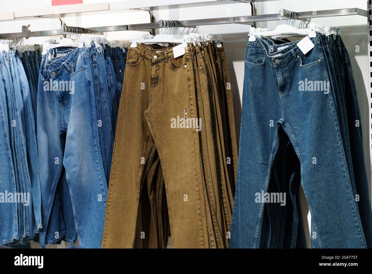 Various styles of denim jeans hang neatly on display racks in a retail ...