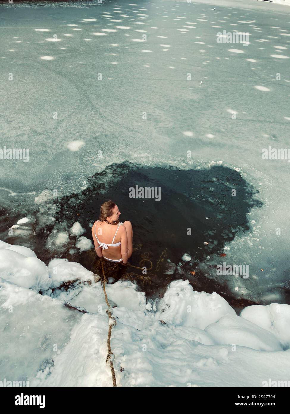 Woman ice cold water swimming in the frozen lake. Ice bath in the ...