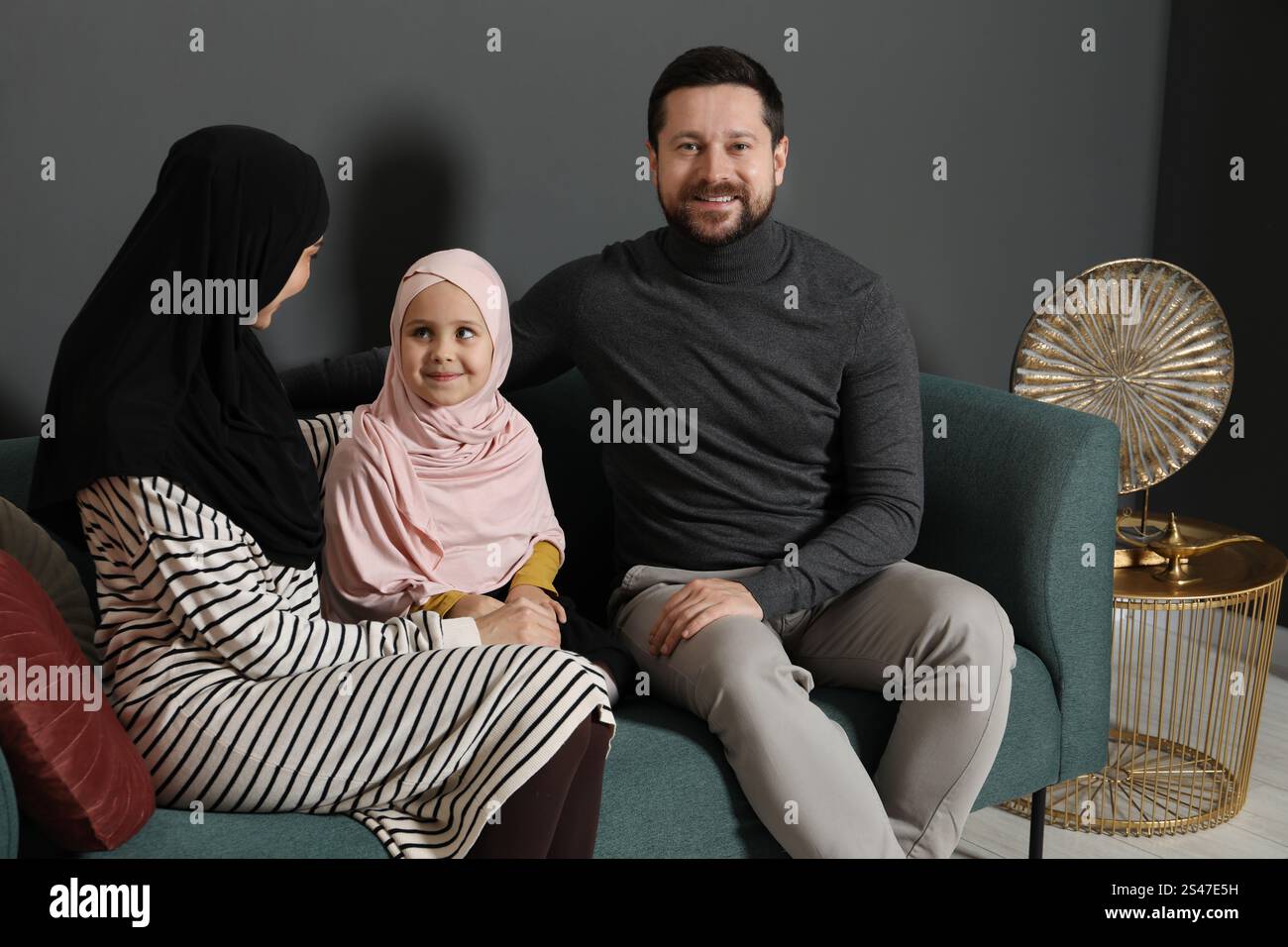 Happy Muslim family sitting on sofa at home Stock Photo - Alamy