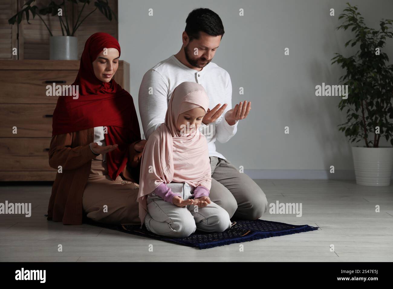 Muslim family praying on mat at home Stock Photo - Alamy