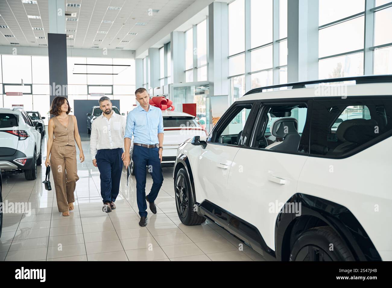 Salesman talking to a young couple at the dealership showroom Stock ...