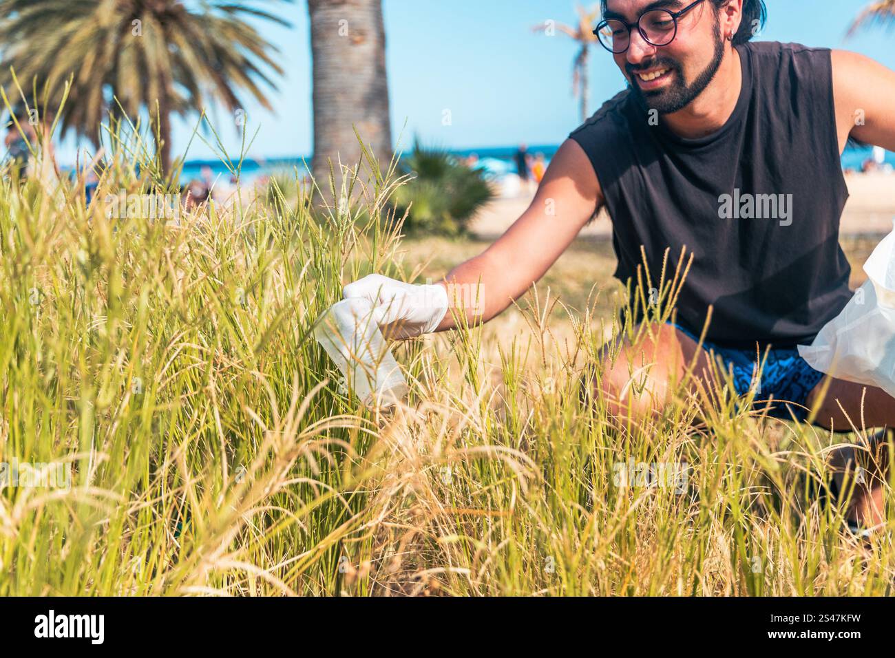 A happy activist is picking up trash in a field taking care of the ...