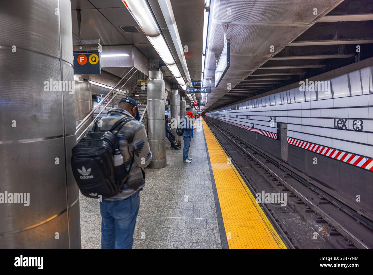 Lexington Avenue subway platform with waiting passengers, illuminated ...