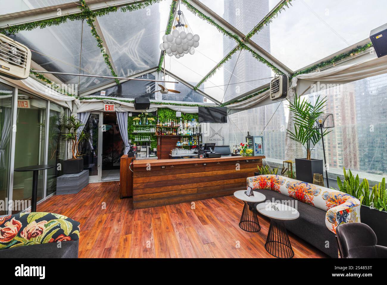 Rooftop lounge with modern bar, colorful seating and greenery under ...