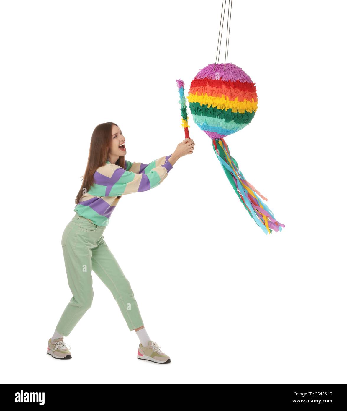 Emotional woman breaking colorful pinata with stick on white background ...