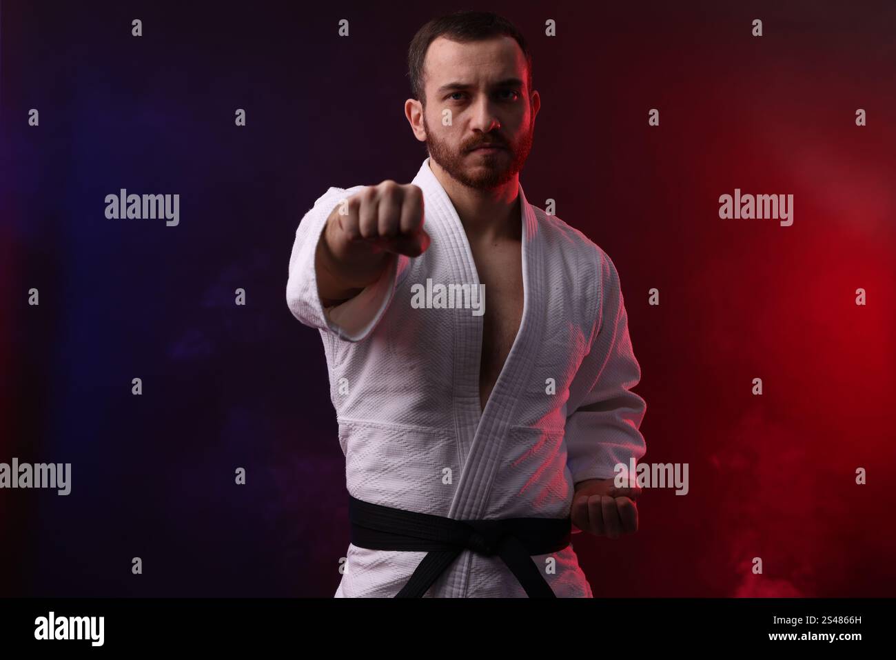 Man wearing uniform practicing karate in color lights and smoke Stock ...