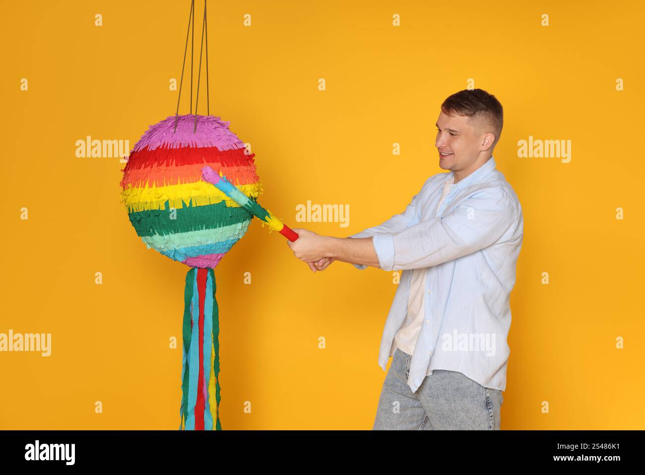 Happy man breaking pinata on yellow background Stock Photo - Alamy