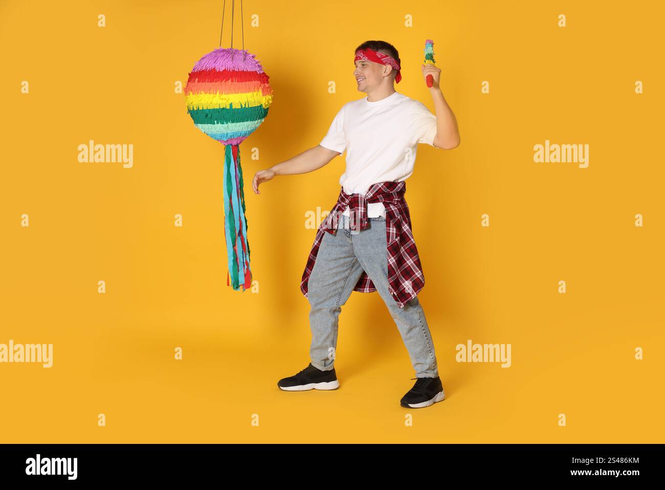 Happy man breaking pinata on yellow background Stock Photo - Alamy