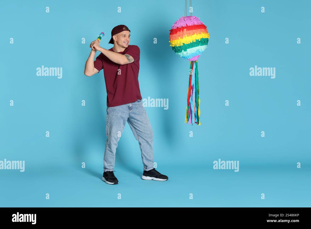 Happy man breaking pinata on light blue background Stock Photo - Alamy