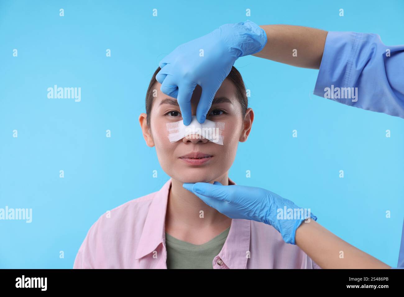 Doctor checking patient's nose after plastic surgery operation on light ...