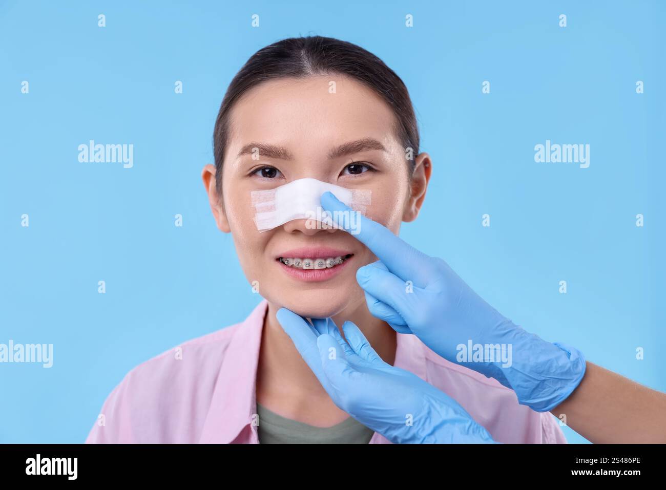 Doctor checking patient's nose after plastic surgery operation on light ...