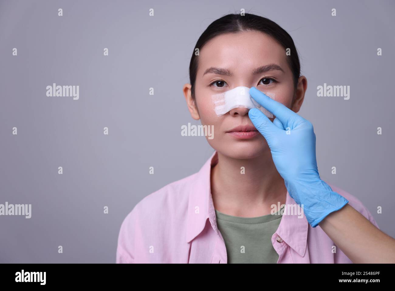 Doctor checking patient's nose after plastic surgery operation on light ...