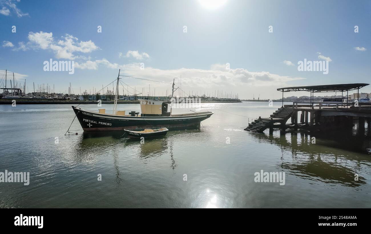 A boat docked along the Arade River in Portimão, Portugal, under clear ...