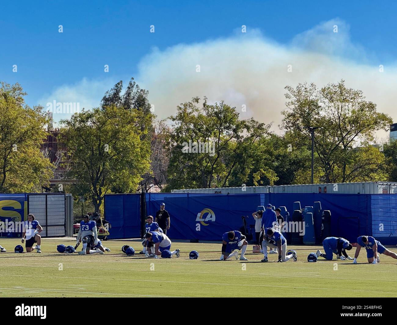 The Los Angeles Rams NFL football team practices under a plume of smoke ...