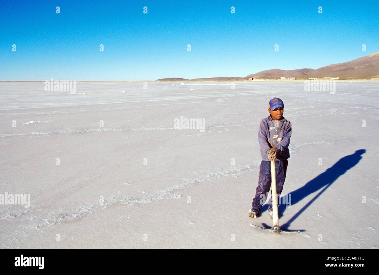 A boy resting while extracting salt in the Coipasa salt flats, Oruro ...