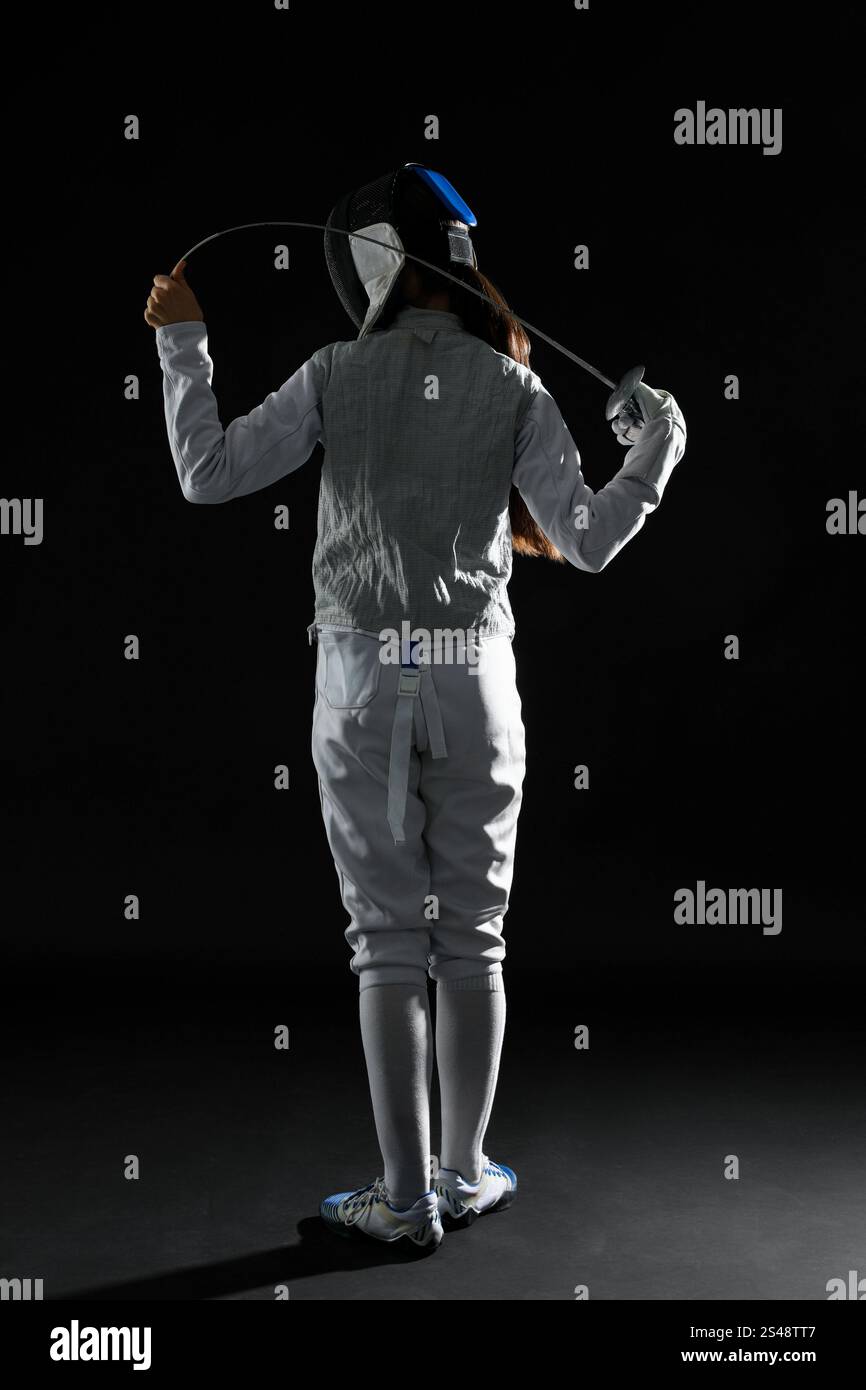 Fencer with epee on dark background, back view Stock Photo - Alamy