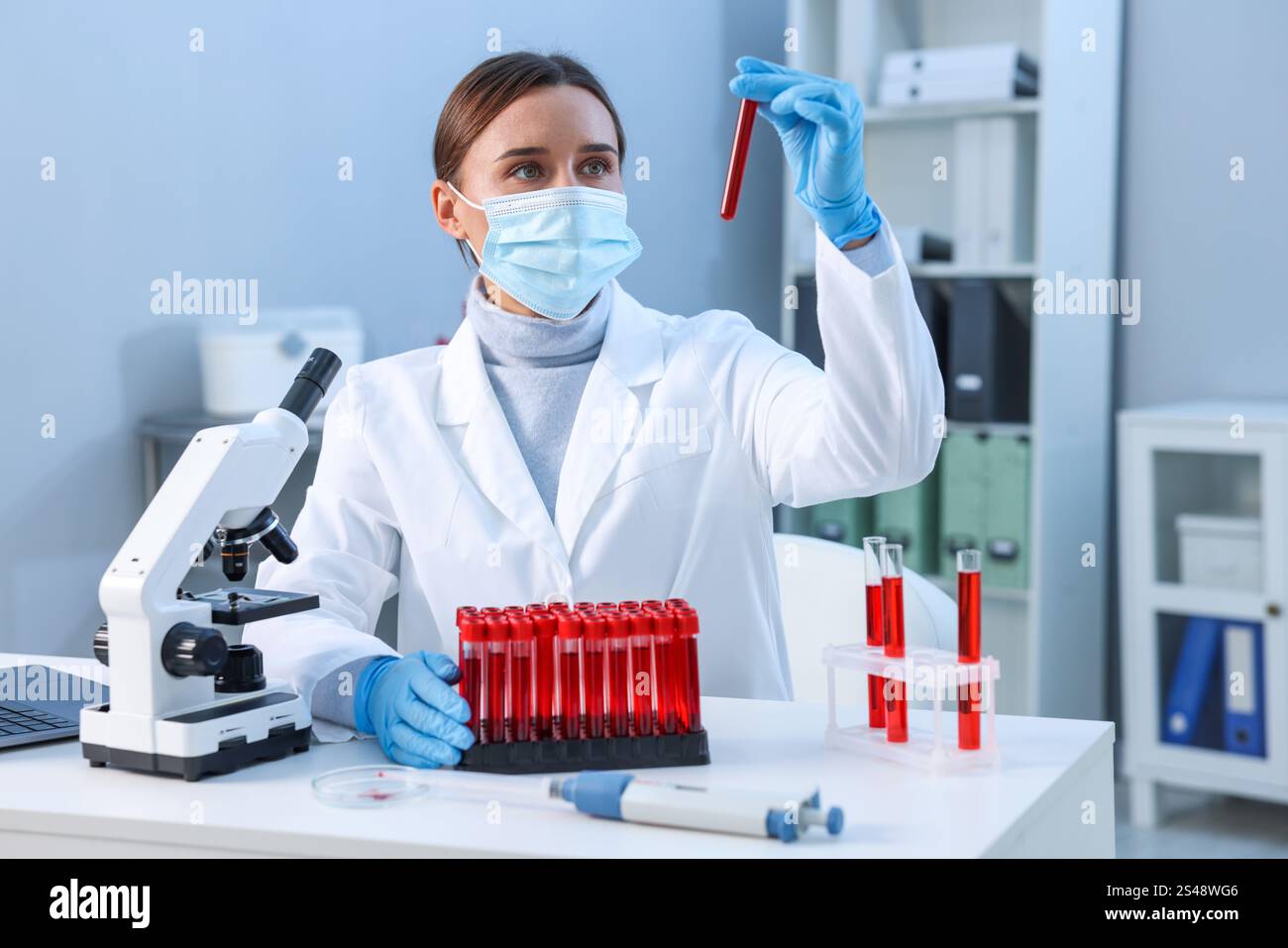 Laboratory testing. Doctor holding test tube with blood sample at table ...