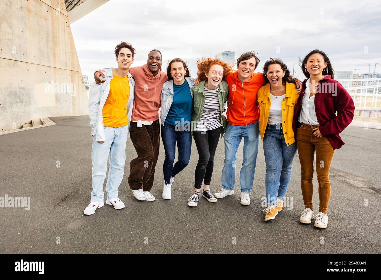 Happy young group of teen friends hugging each other smiling at camera ...