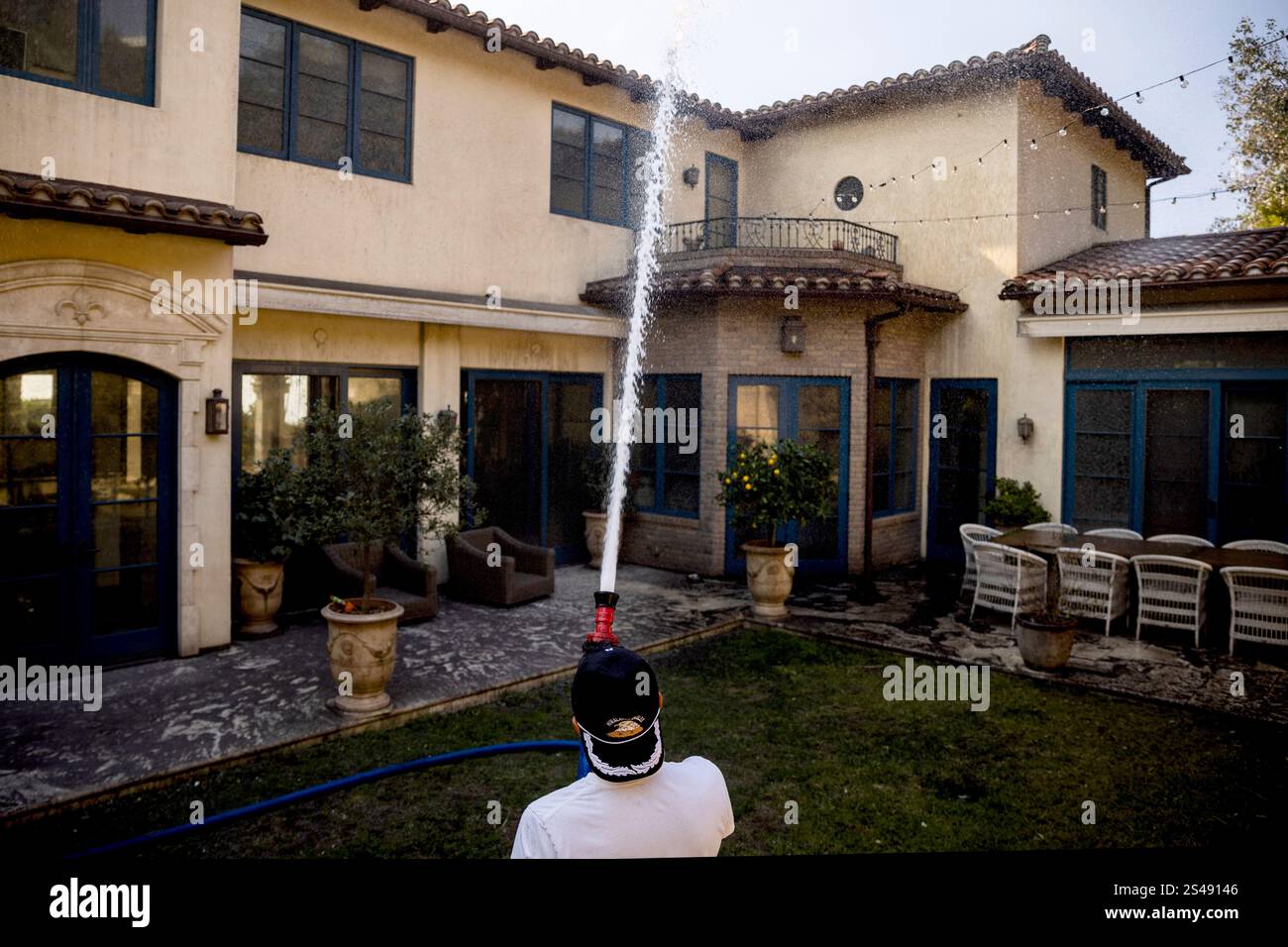 Neil Desai hoses down his intact home after successfully defending it ...