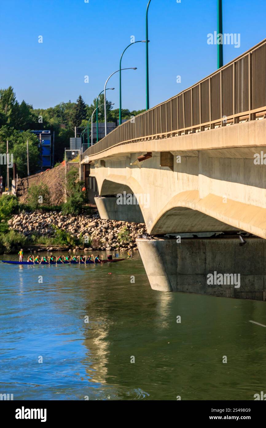 A bridge spans a river with a group of people rowing boats on the water ...