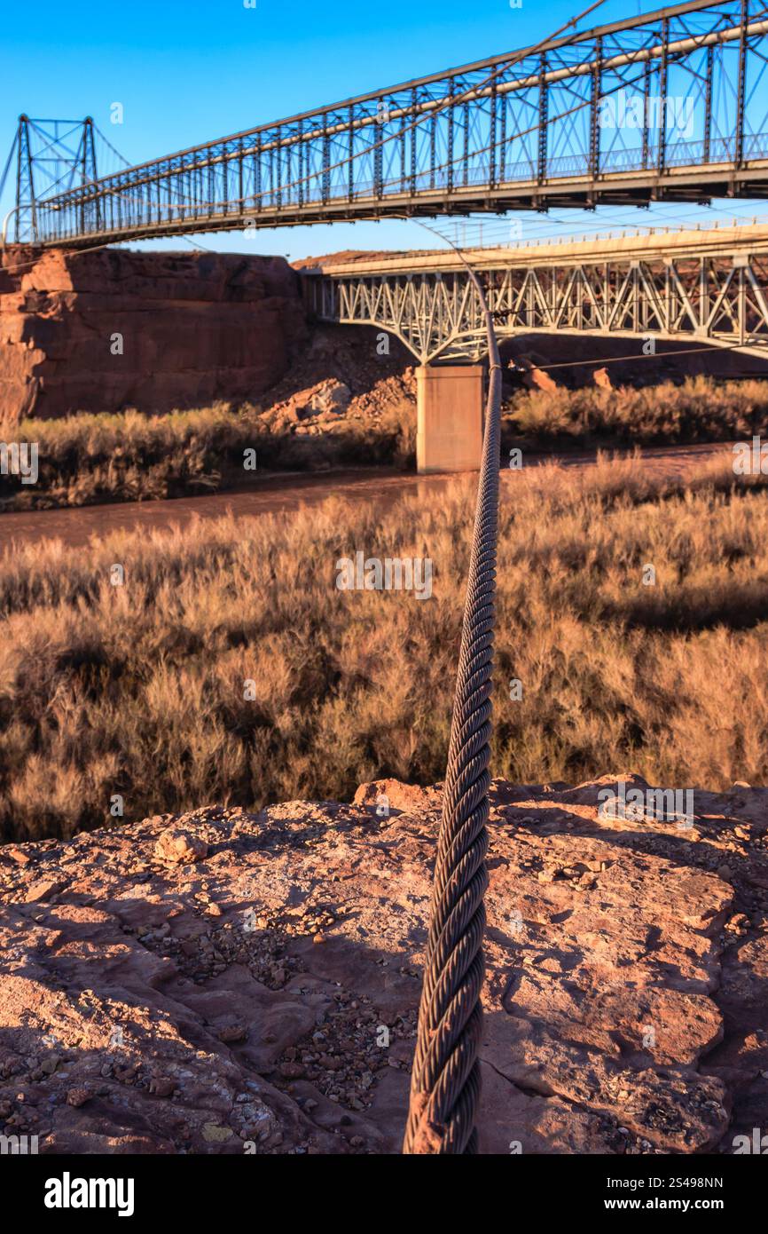 A bridge spans a river with a rope hanging from it. The rope is tied to ...