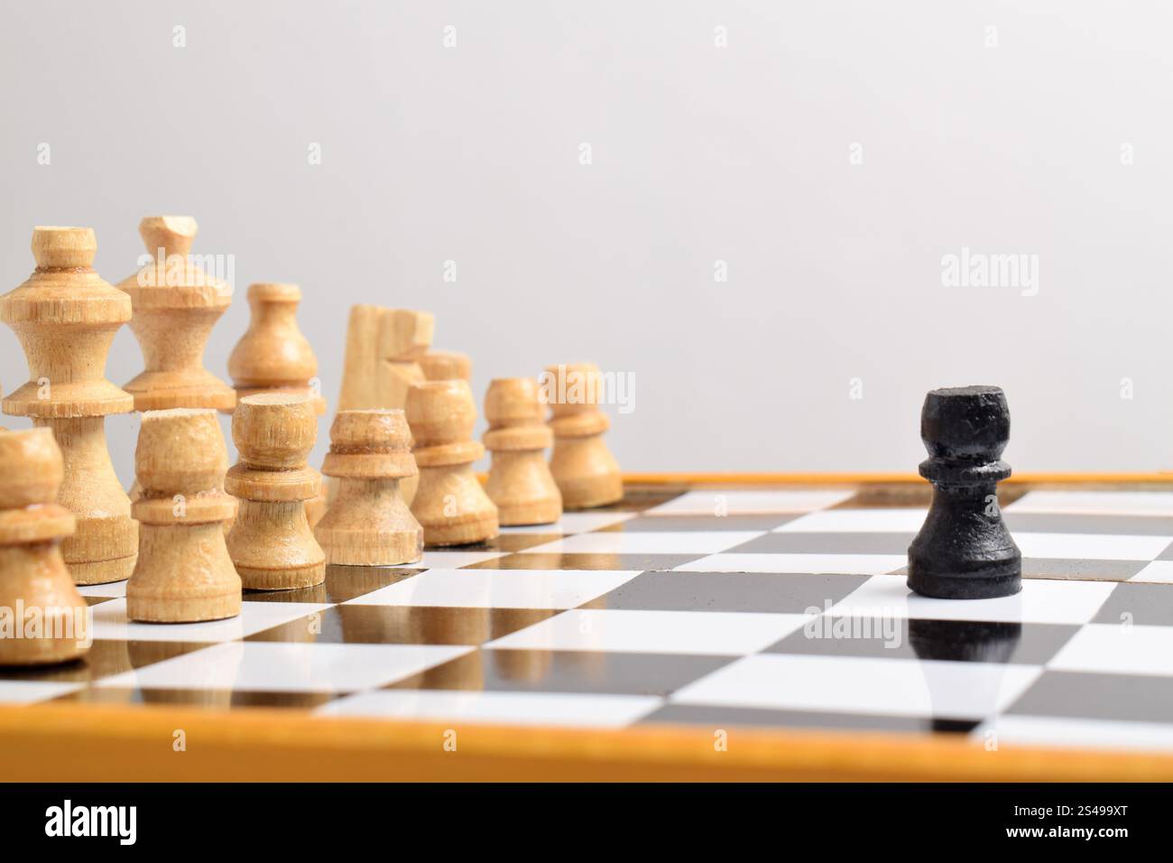 Black chess pawns facing row of white chess pieces Stock Photo - Alamy