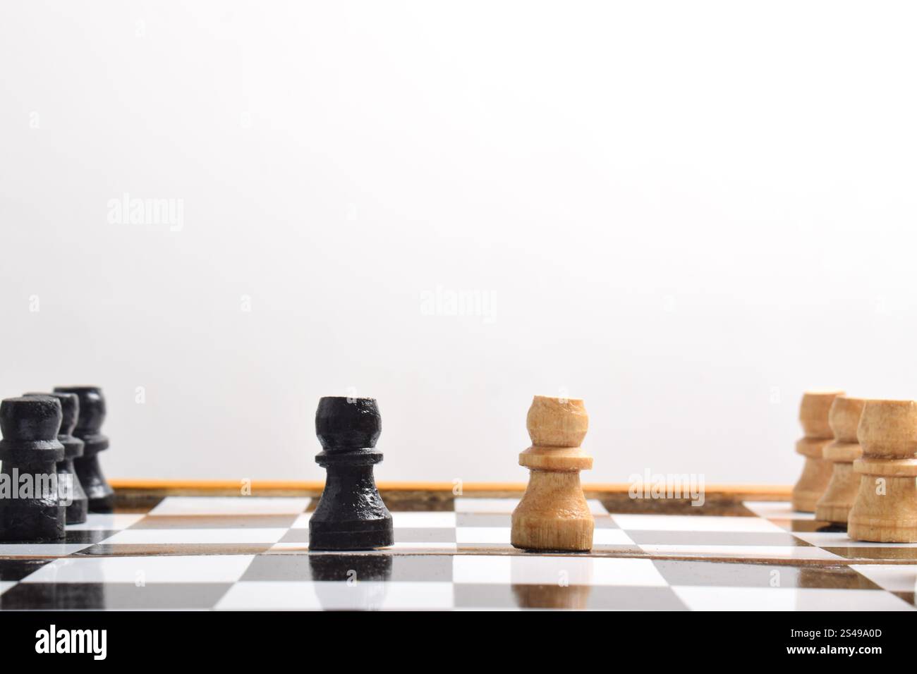 White chess pieces face off black chess pieces on white background ...