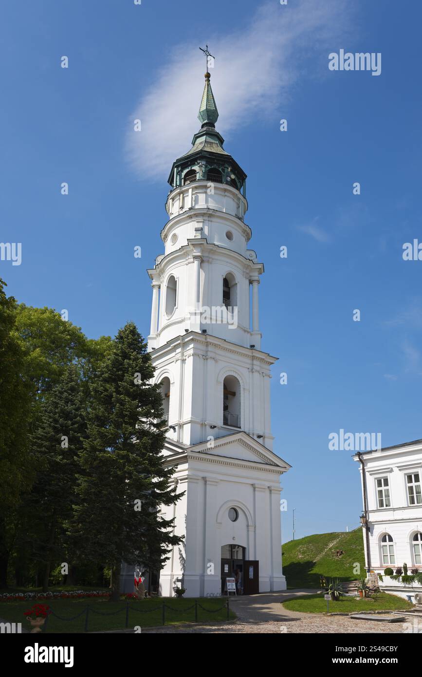 Large white church tower next to trees under a blue sky, bell tower of ...