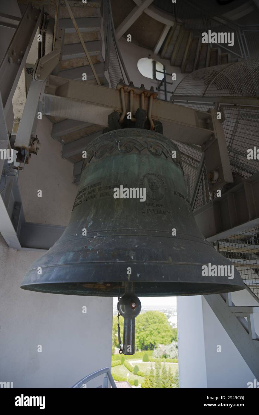 Large metal bell inside a tower with a spiral staircase and a view of ...