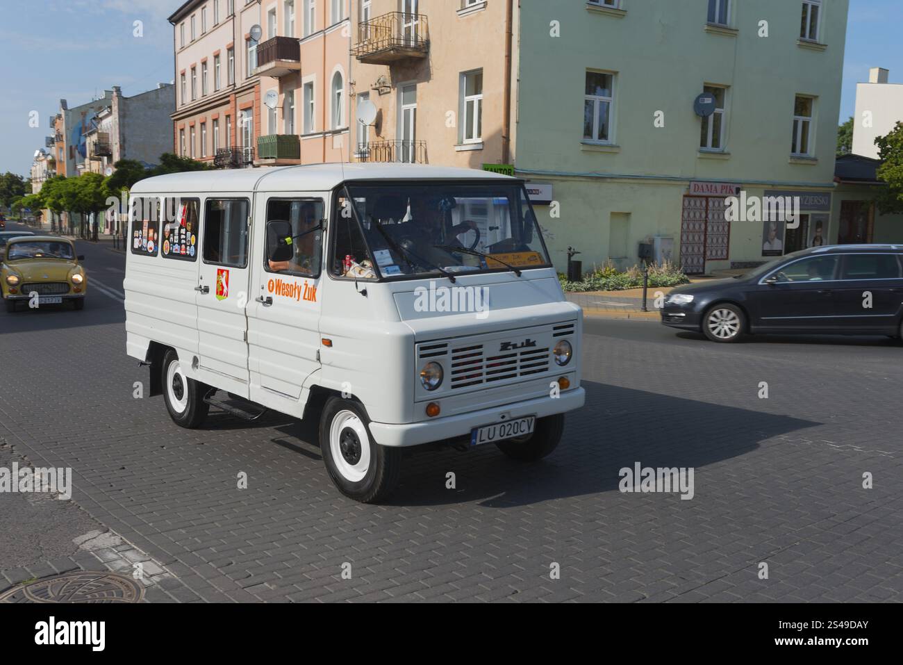 Minibus driving on city street, surrounded by historical buildings ...