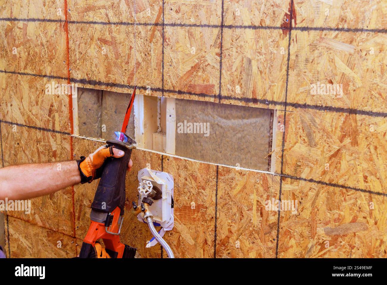 Contractor uses saw to cut through an oriented strand board wall for ...