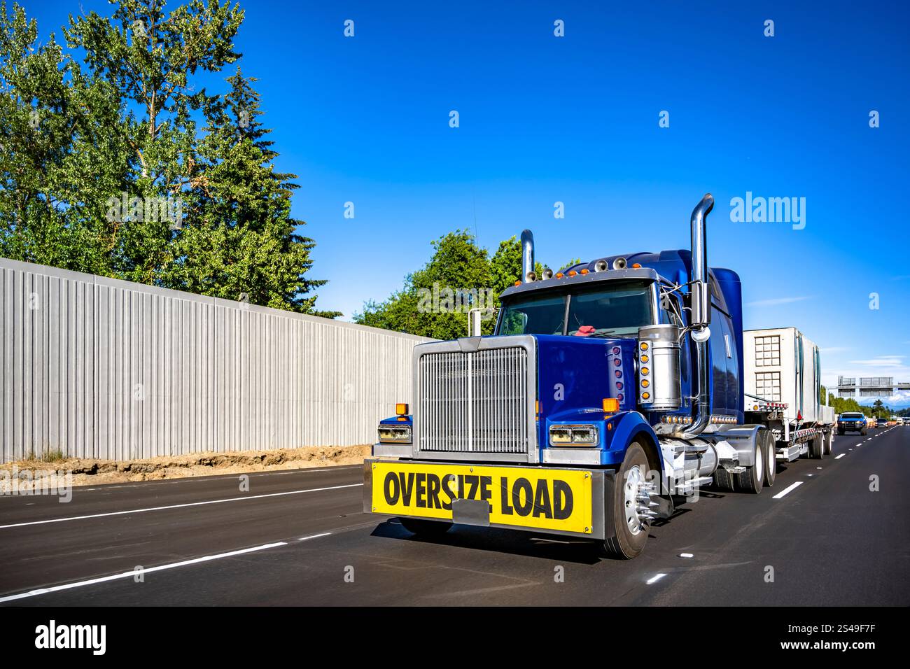 Industrial bright blue big rig semi truck with oversize load sigh on ...