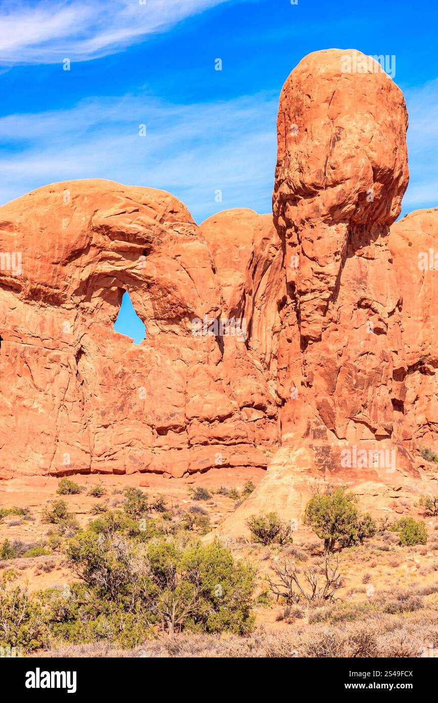 A large rock formation with a small hole in the middle. The sky is blue ...