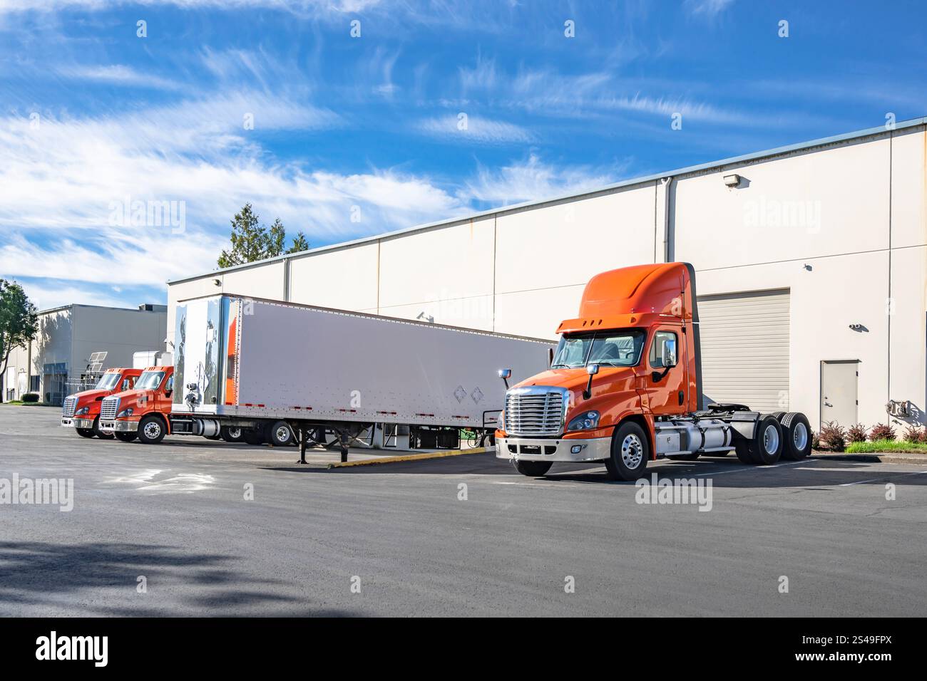Industrial bright orange day cab big rig semi trucks and dry van semi ...