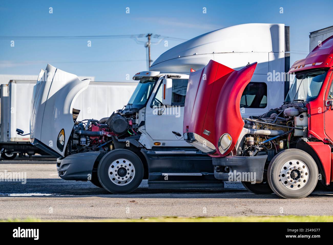 Big rig semi trucks with open hoods and semi trailers standing in row ...