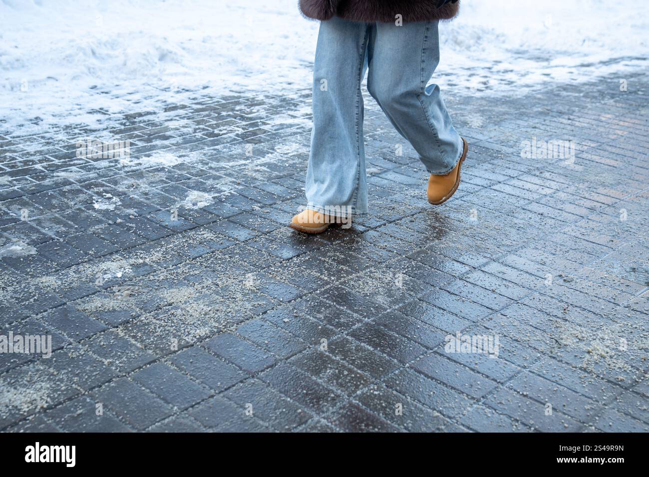 Anti-icing chemicals. Woman walking on the street treated with ...