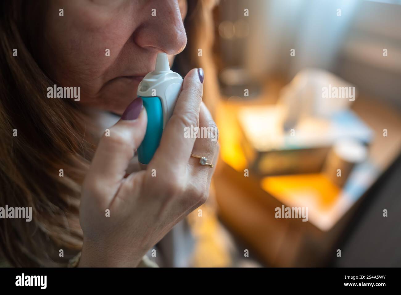 Woman pouring drops with an inhaler into her nose to breathe better ...