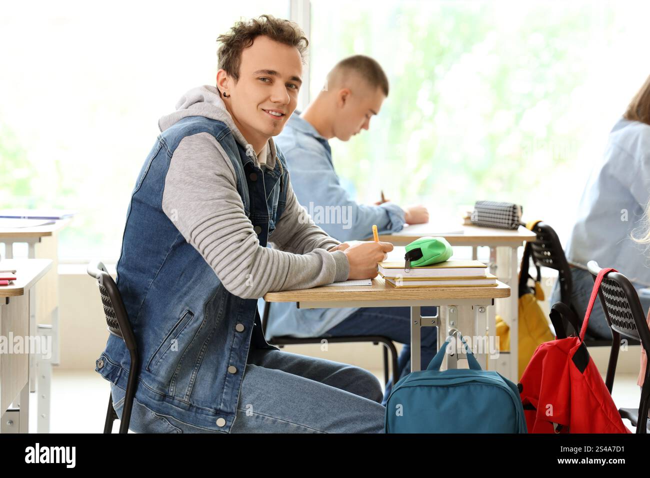 Happy male student sitting with his classmates in classroom Stock Photo ...