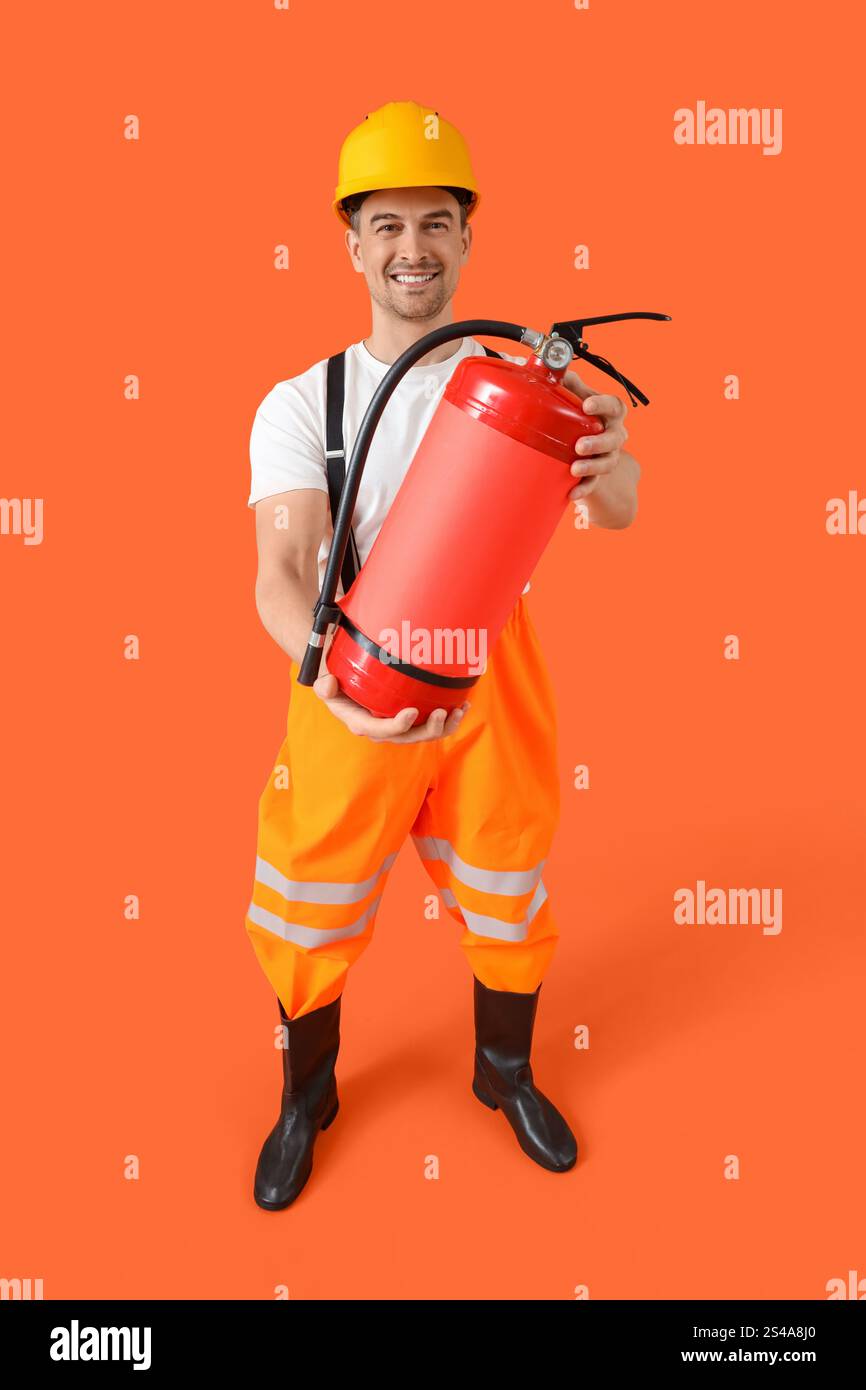 Firefighter with fire extinguisher on orange background Stock Photo - Alamy